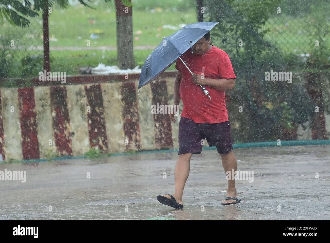 People crossing a deserted road in heavy rain during Cyclone Remal in ...