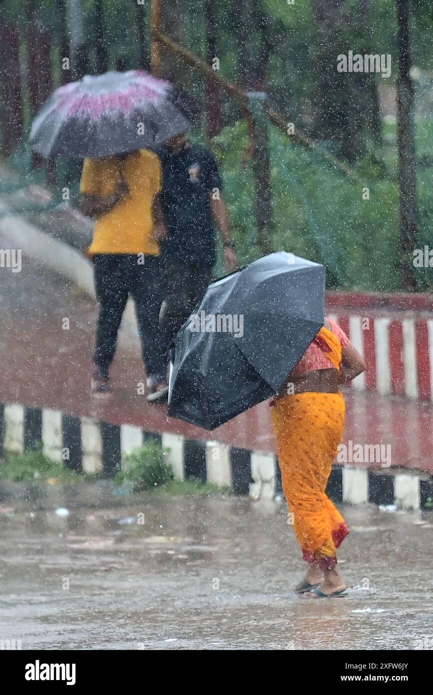 People crossing a deserted road in heavy rain during Cyclone Remal in ...