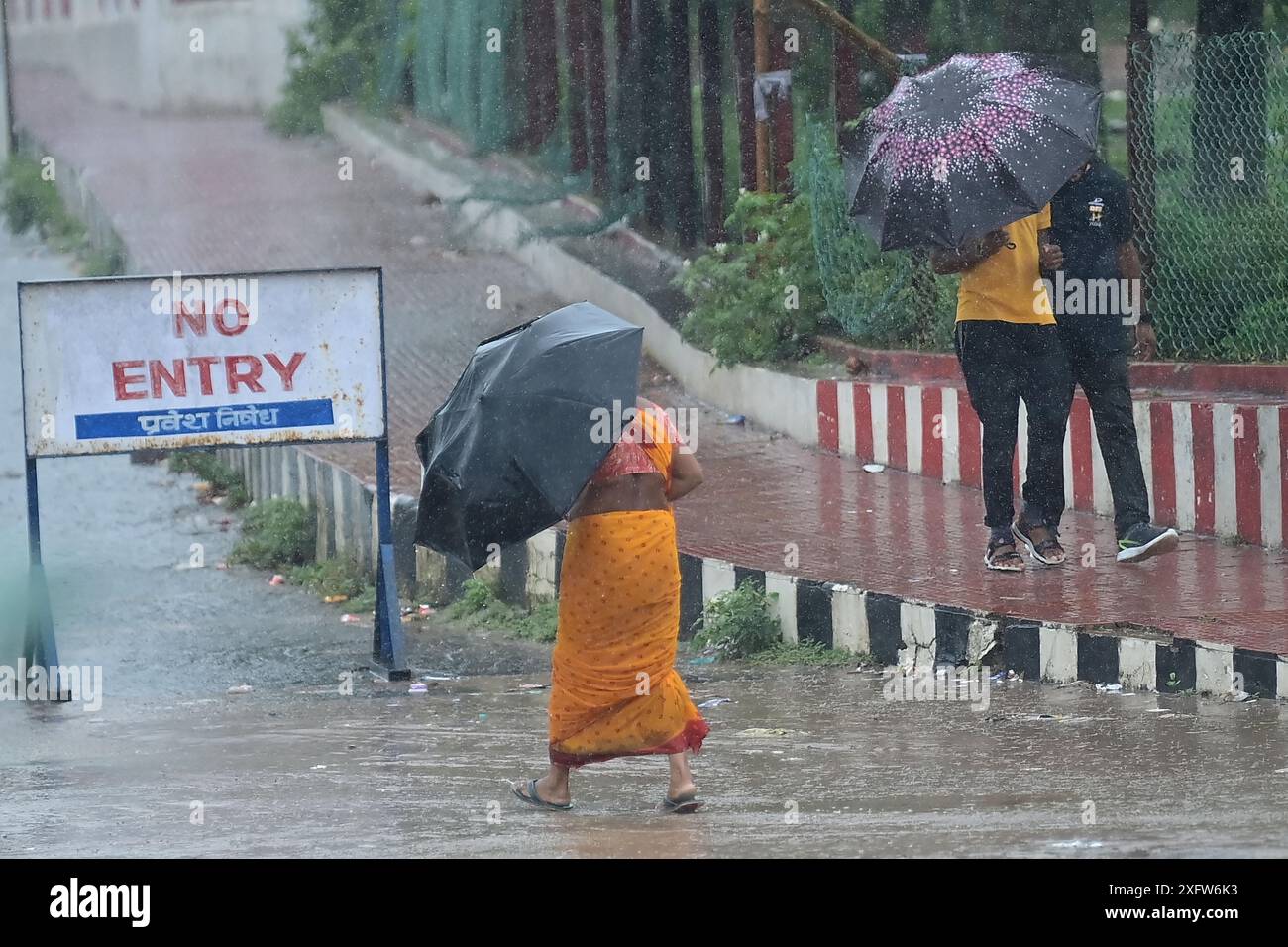 People crossing a deserted road in heavy rain during Cyclone Remal in ...