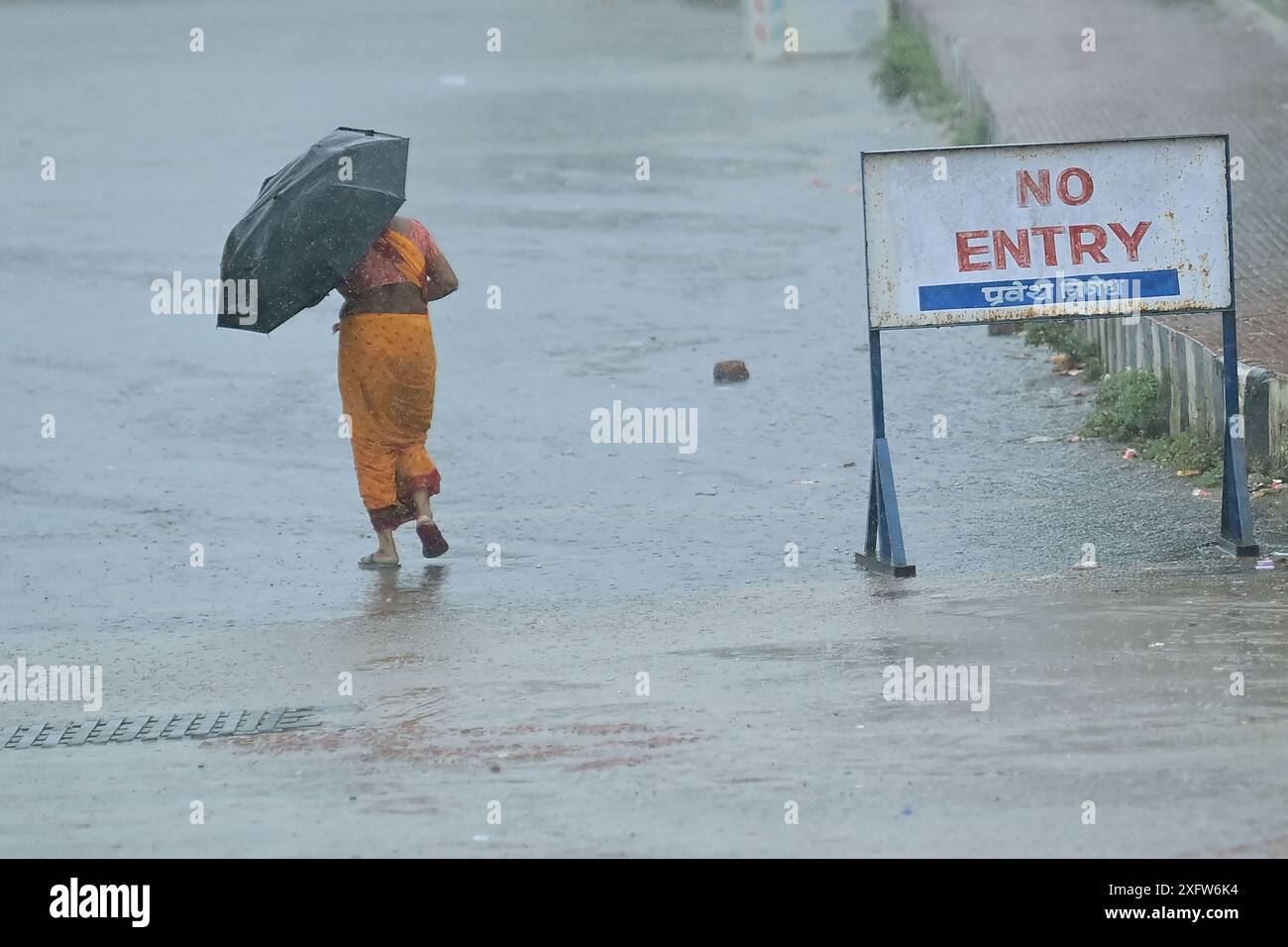 A woman crossing a deserted road in heavy rain during Cyclone Remal in ...