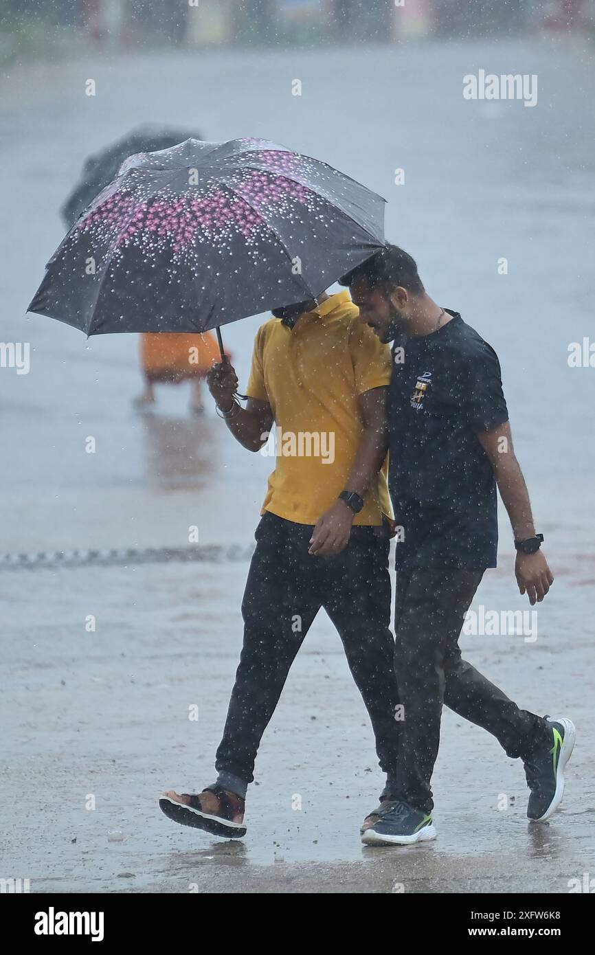 People crossing a deserted road in heavy rain during Cyclone Remal in ...