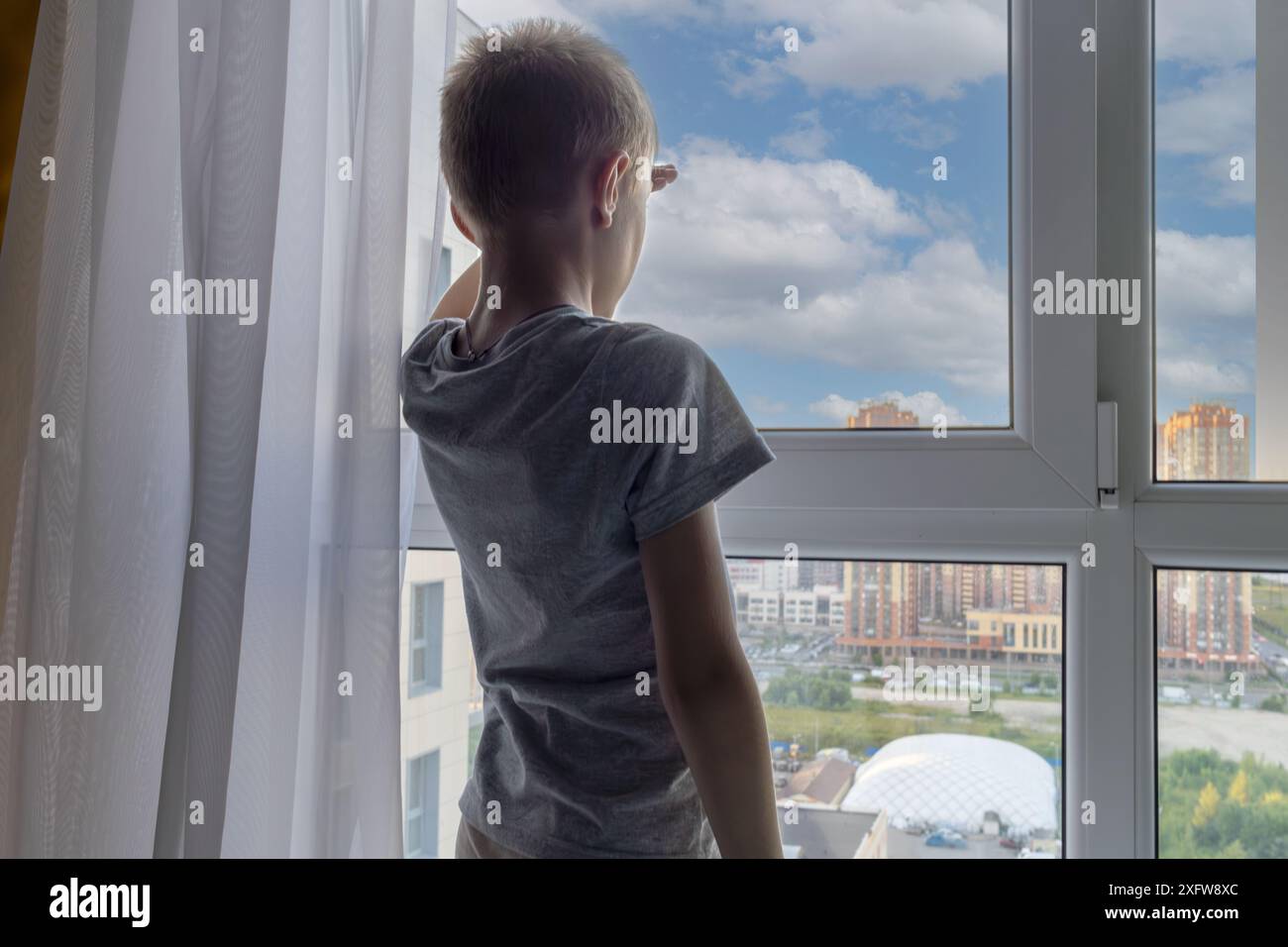 Boy looks out window at city, dreaming of future. Self-knowledge in pre ...