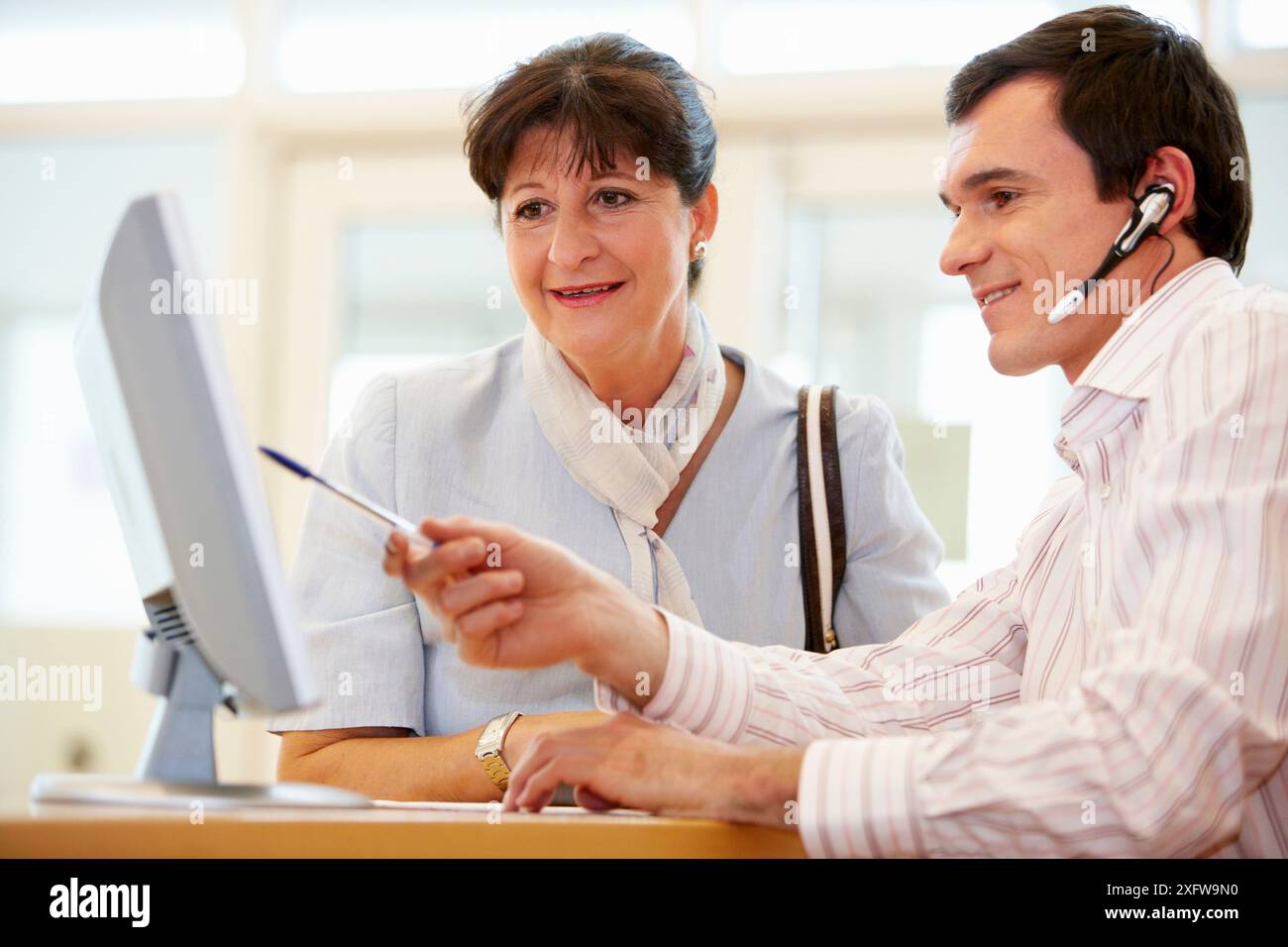 Office worker giving information to retired woman Stock Photo - Alamy
