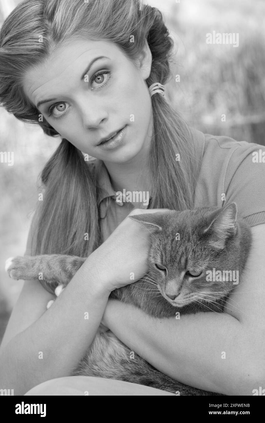 Caucasian teen girl lovingly stroking her gray tabby cat, showcasing ...