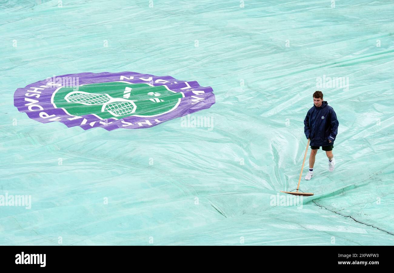 Ground staff sweep standing water off the outside courts on day five of ...