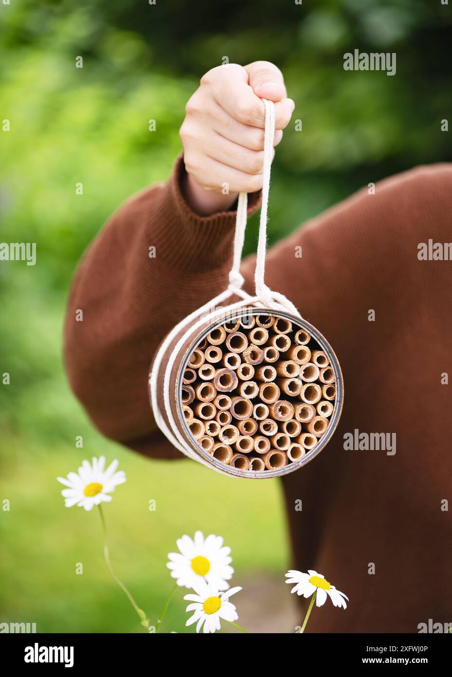 Handmade bug hotel in a girl's hand ready for hanging in summer garden ...