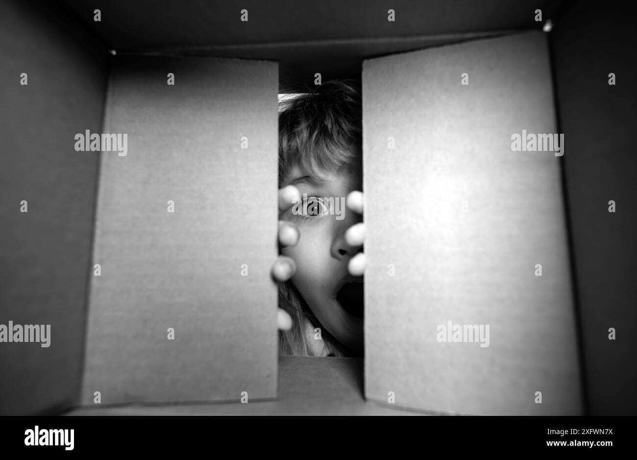 Child boy opening a carton box and looking inside, unpacking concept ...