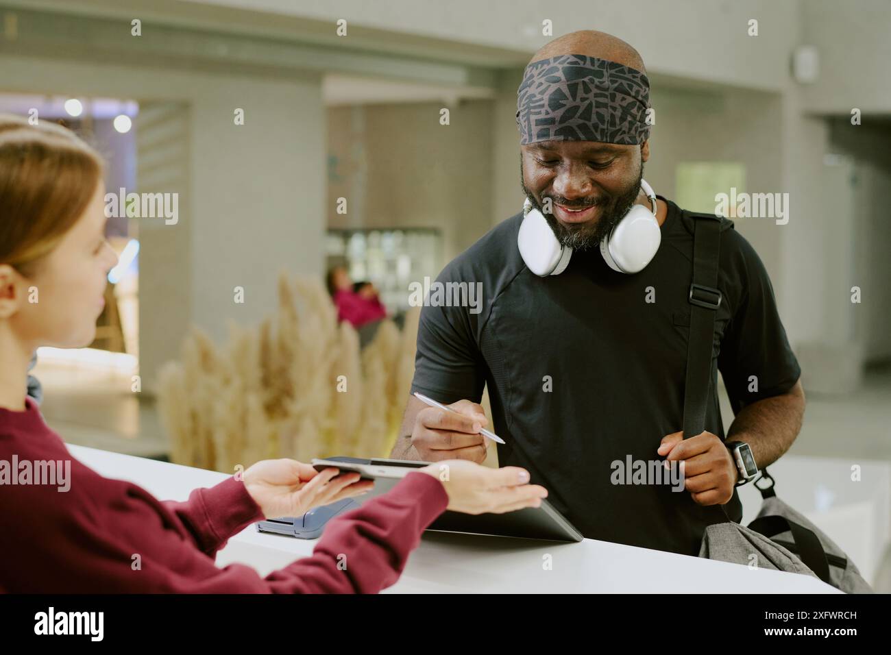 Positive African American man signing gym contract, female receptionist ...