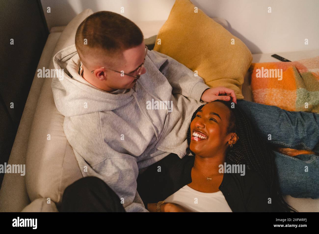 High angle view of happy woman lying down on boyfriend's lap at home ...