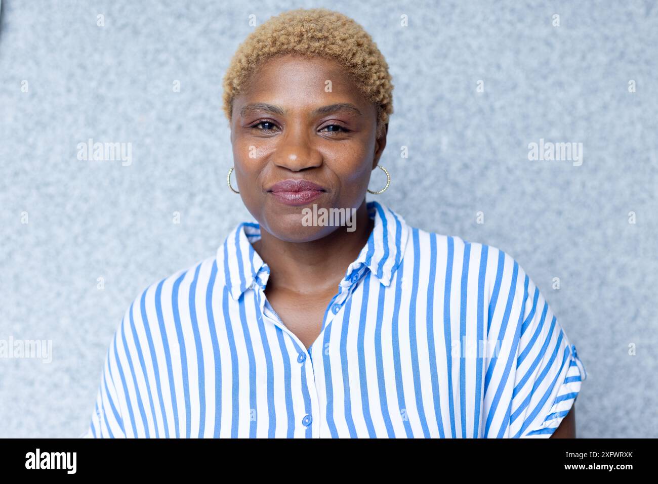 Smiling african american woman in striped shirt posing confidently ...