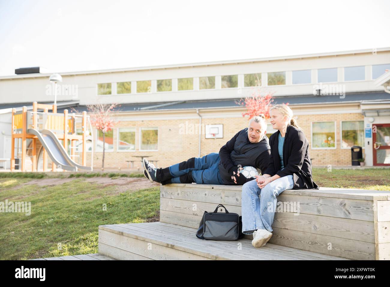 Soccer coach and student sitting on bench at schoolyard Stock Photo - Alamy