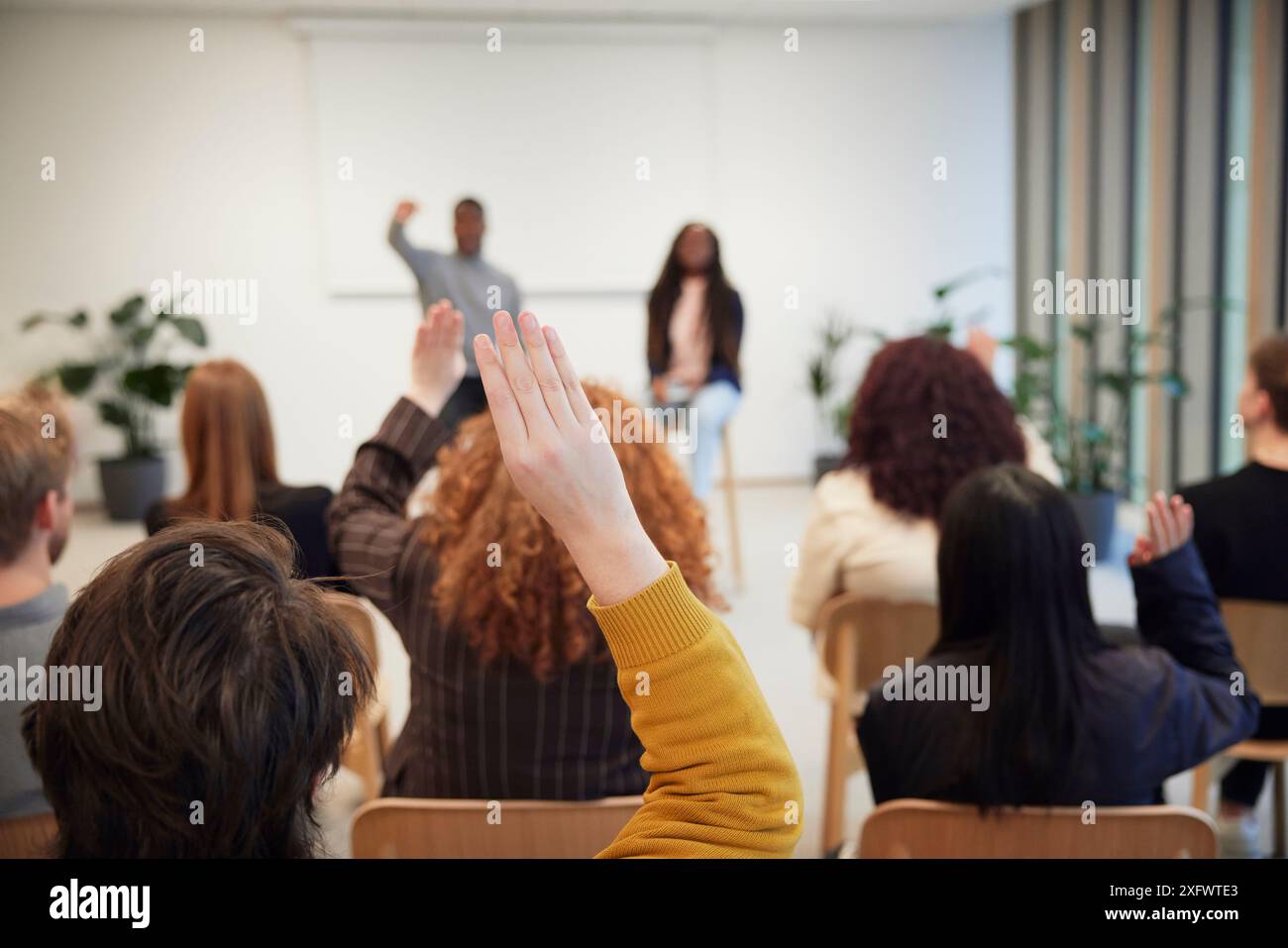 Corporate colleagues raising hands during meeting in office Stock Photo ...