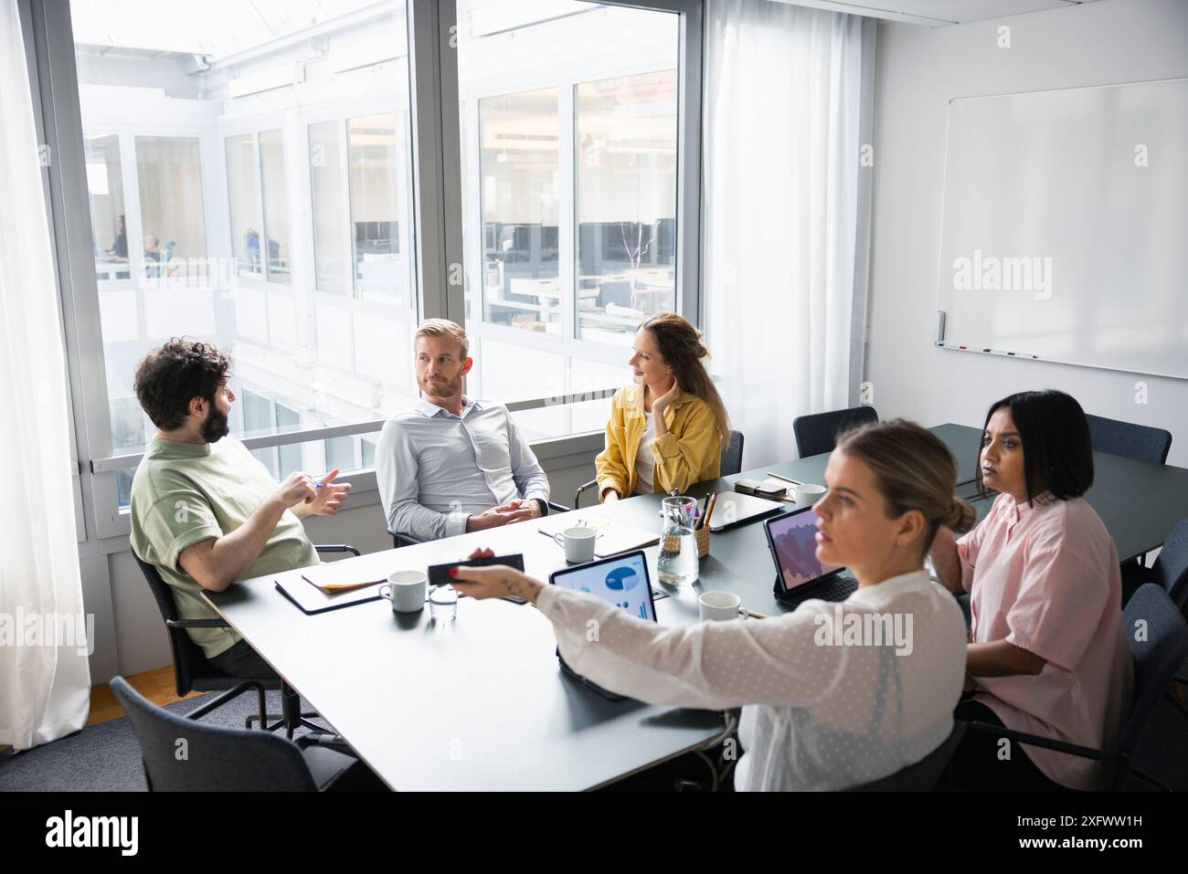 Group of corporate colleagues sitting over conference table in meeting ...