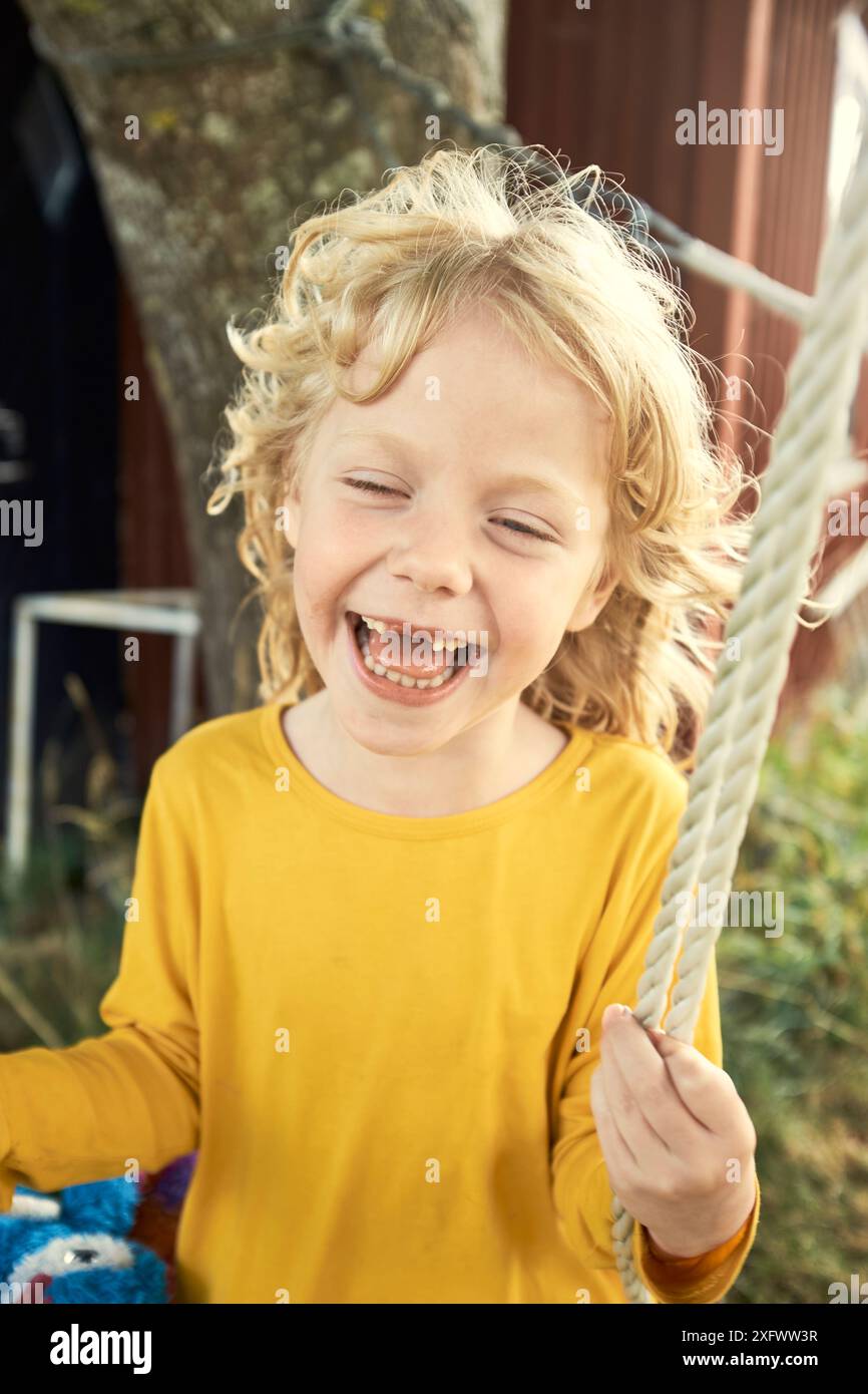 Happy girl with missing teeth swinging in back yard Stock Photo - Alamy