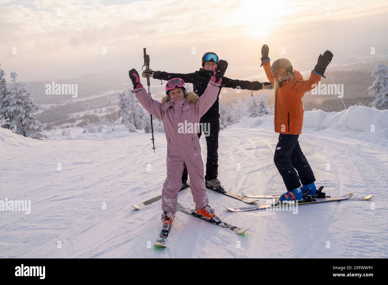 Mother and daughters with arms outstretched skiing at sunset Stock ...