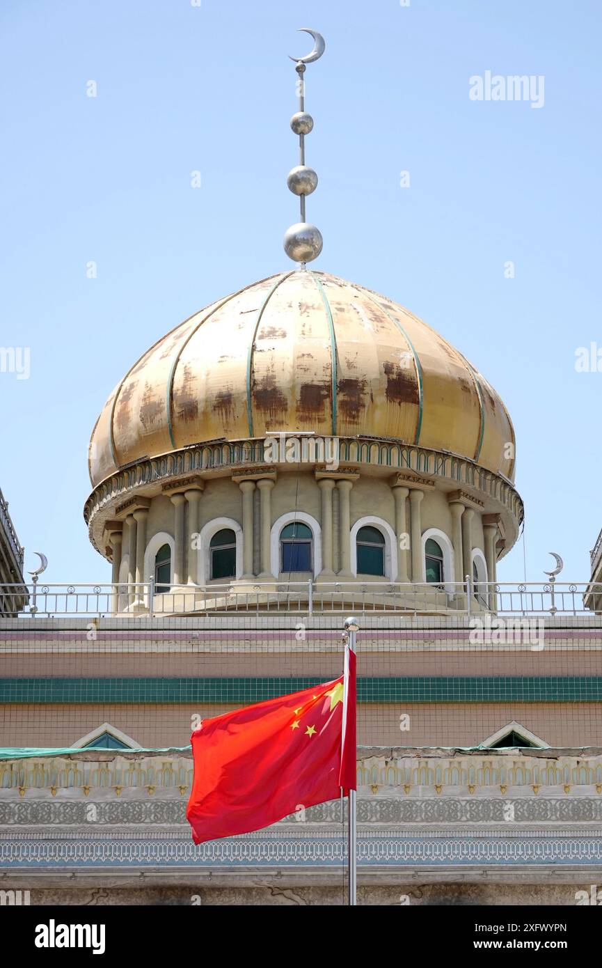 The Chinese national flag is hoisted in front of a mosque in Urumqi in ...
