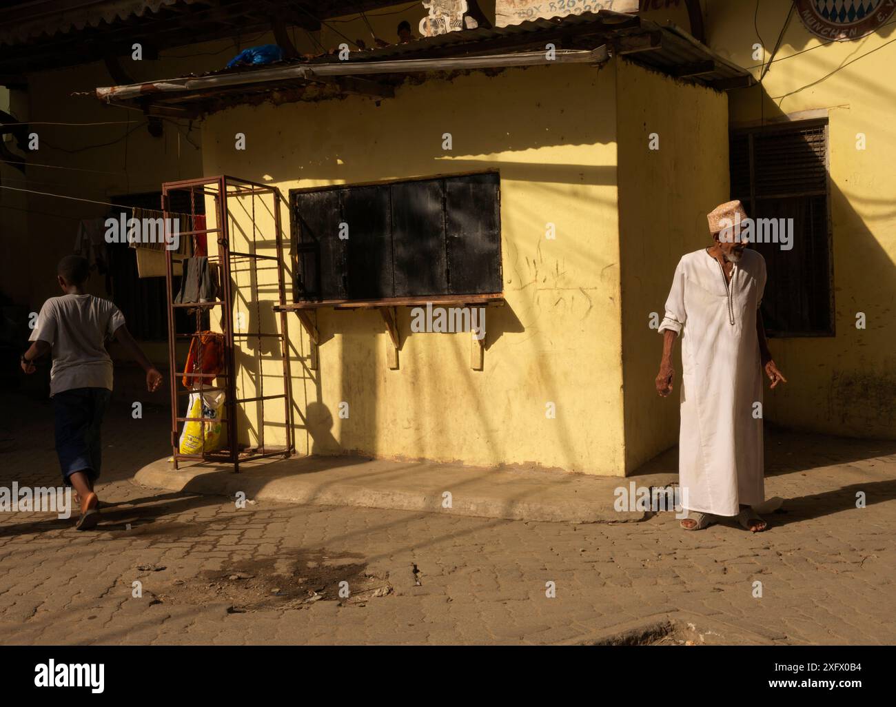 Evening sunlight in Old Town Mombasa with an old man wearing ...