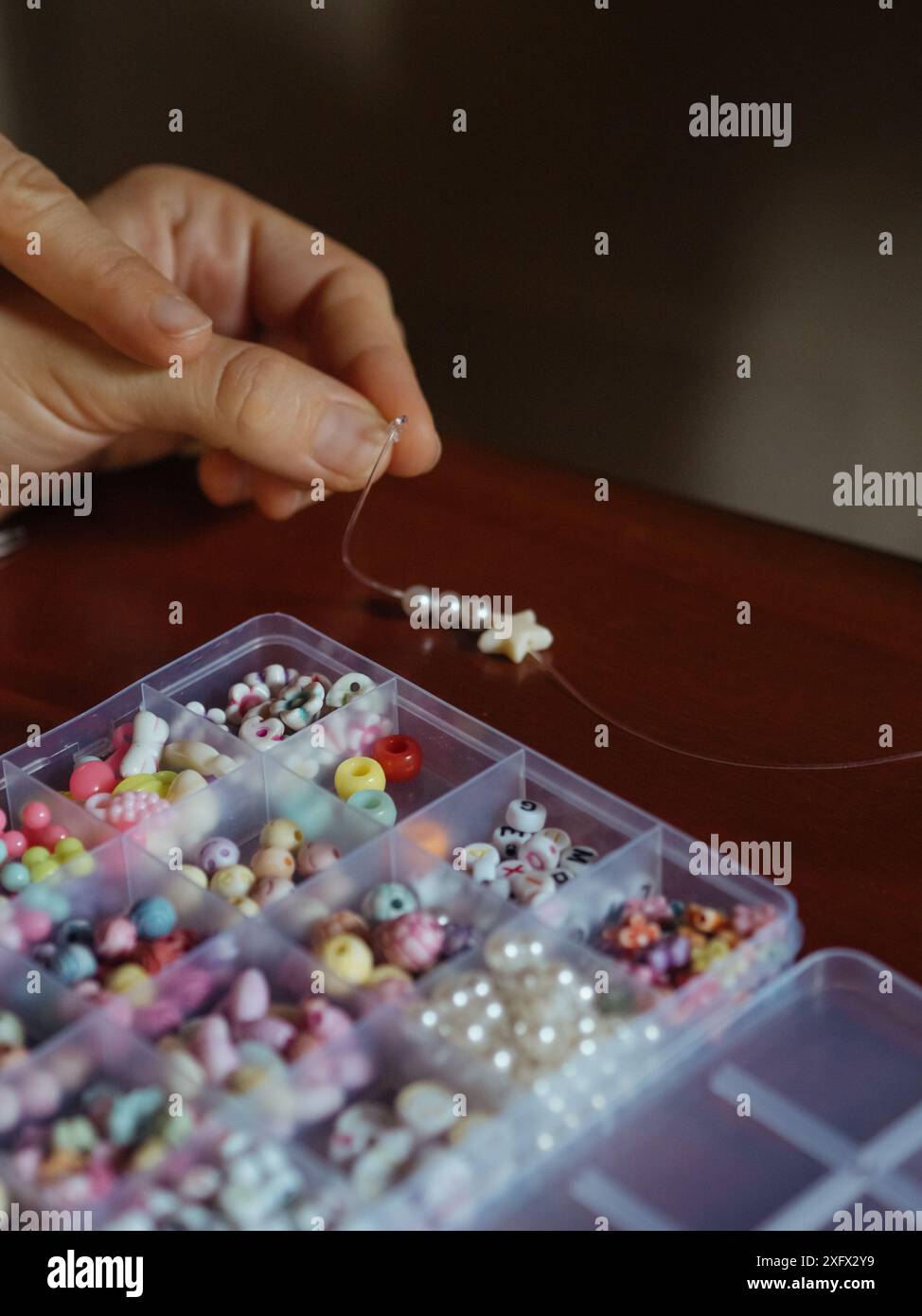 Kid Craft with Beads: A vertical close-up shot captures a woman’s hands ...