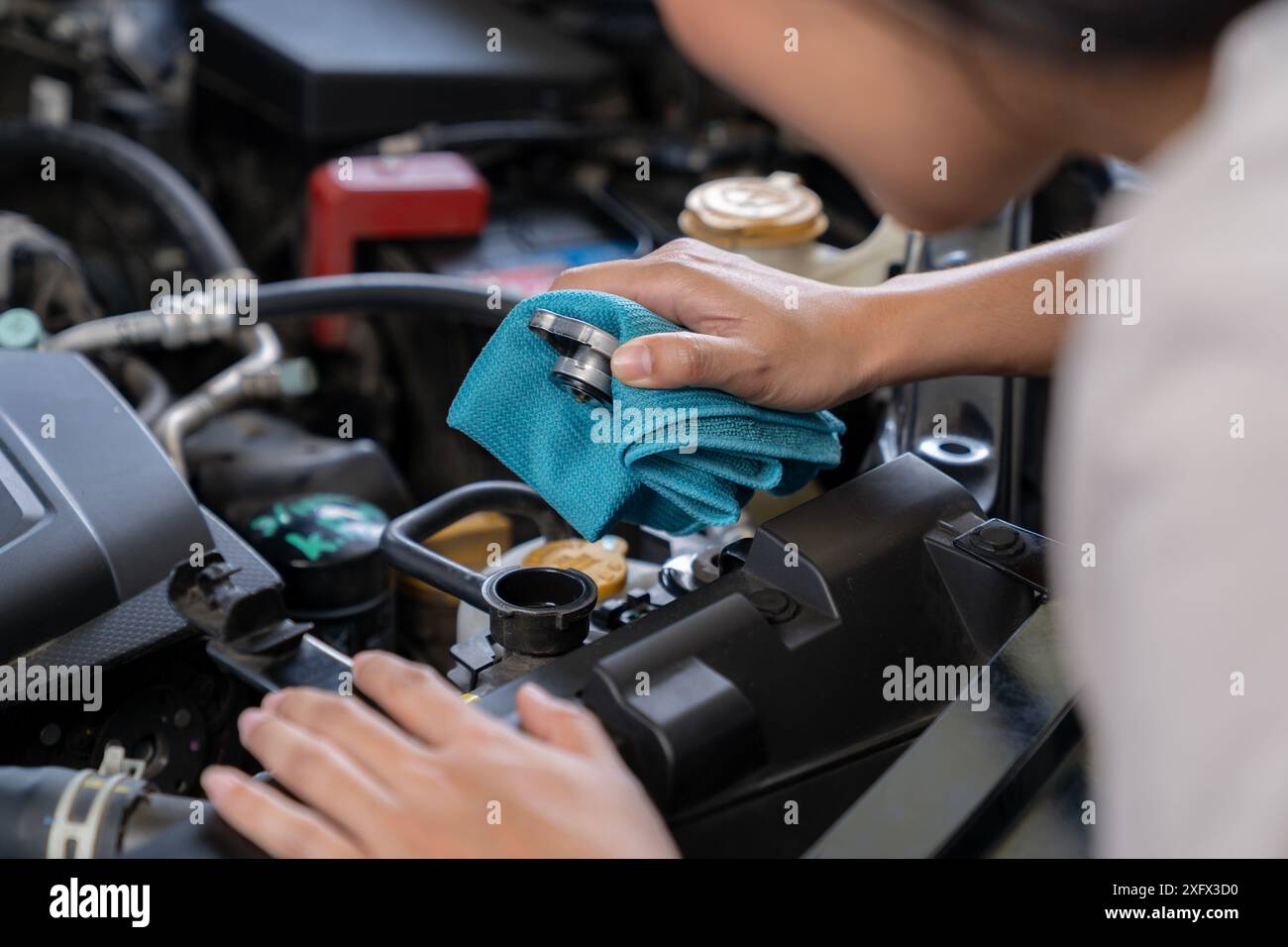 A young woman is checking the car radiator, regularly inspecting and ...