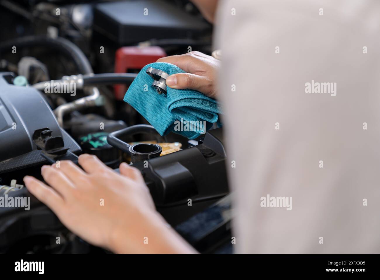 A young woman is checking the car radiator, regularly inspecting and ...