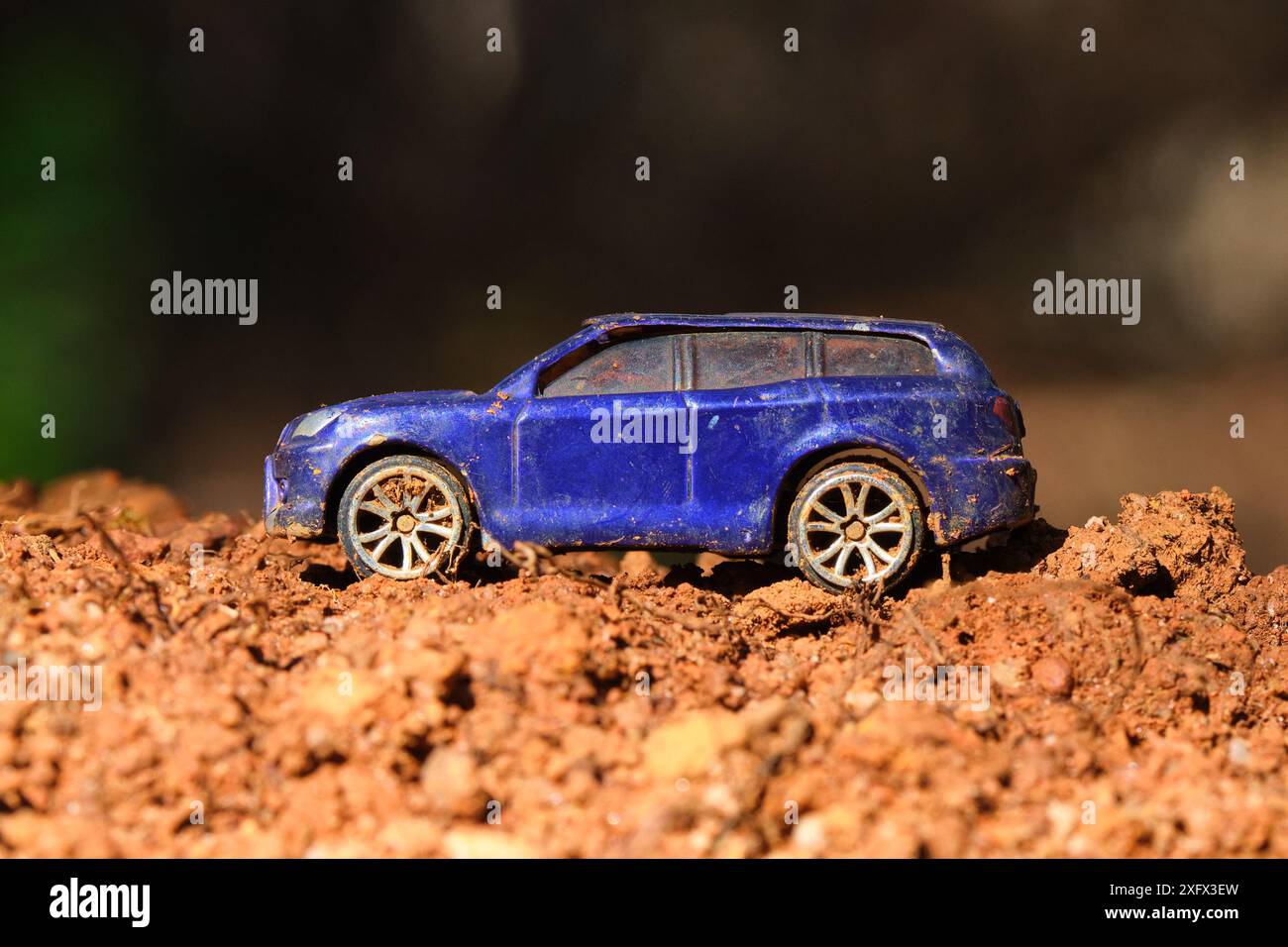 A close-up of a worn and damaged blue toy car in the style of an SUV ...