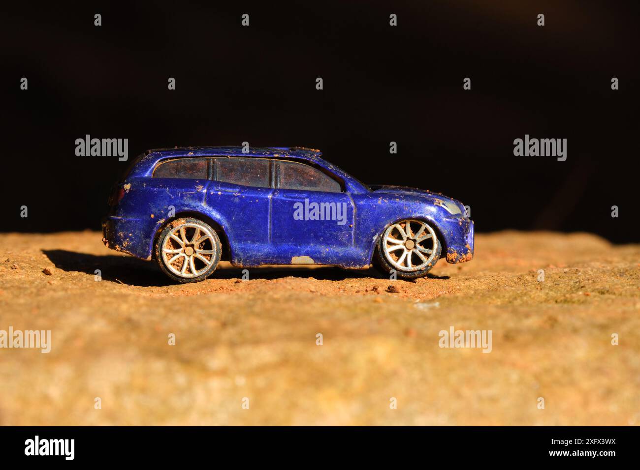 A close-up of a worn and damaged blue toy car in the style of an SUV ...