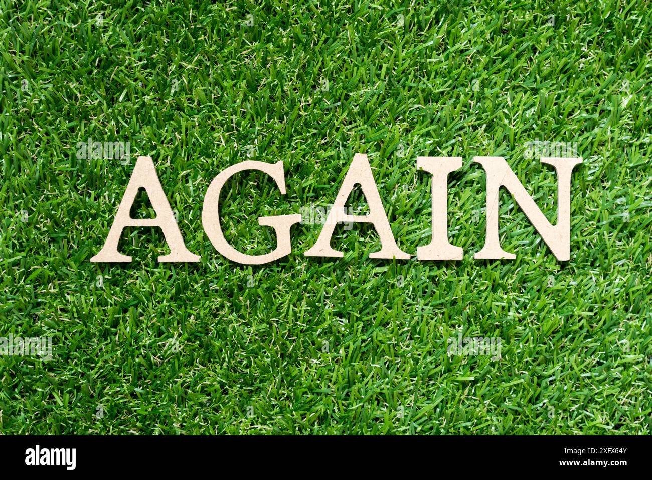 Wood alphabet letter in word again on artificial green grass background ...