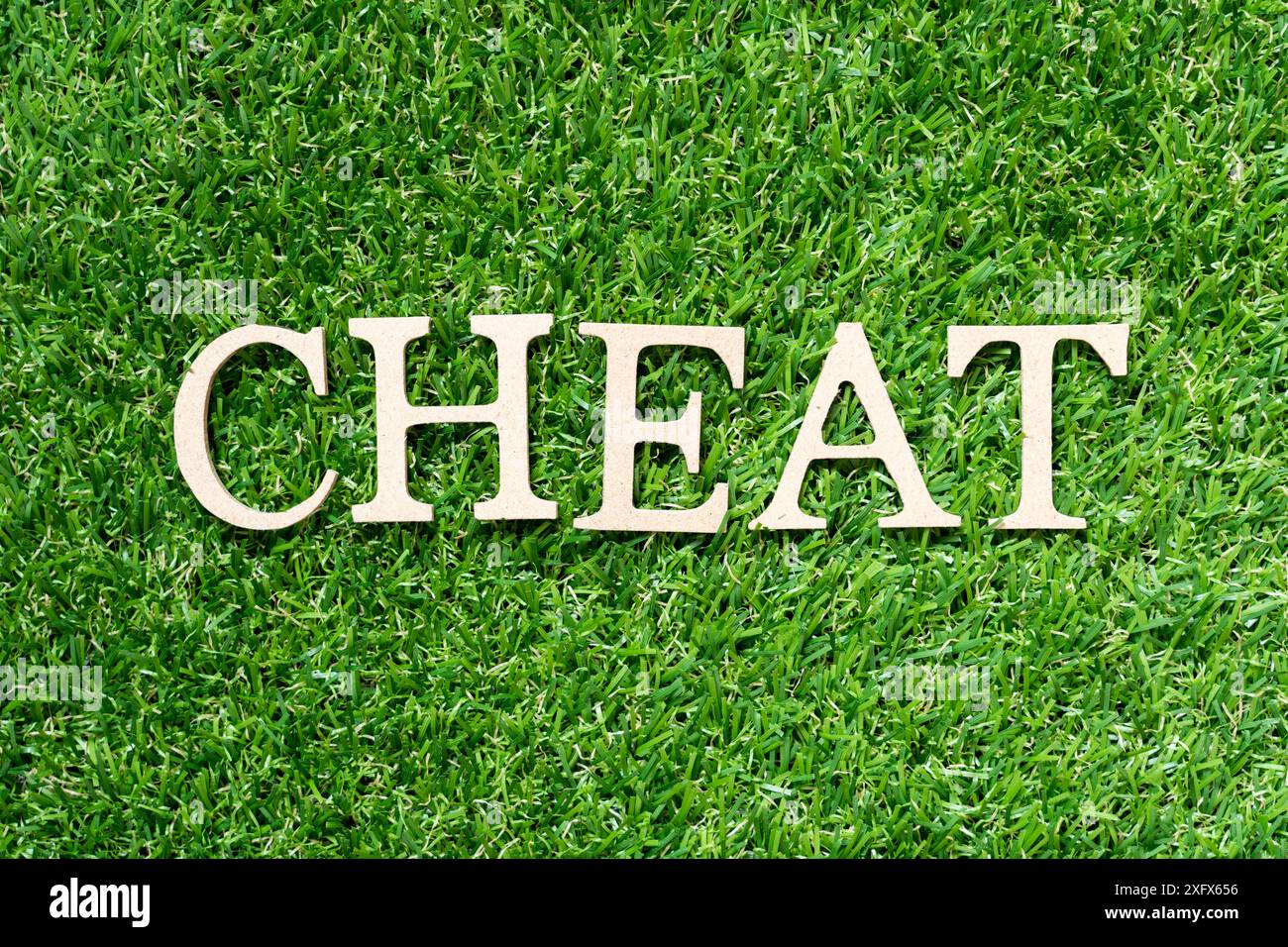 Wood alphabet letter in word cheat on artificial green grass background ...