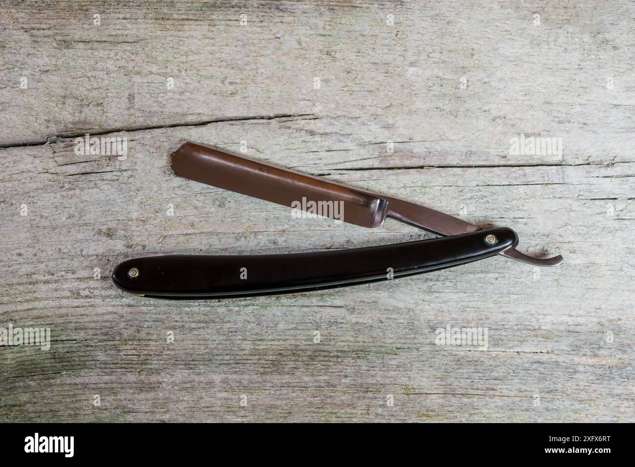 Horizontal close-up photo of vintage straight razor with black scales ...