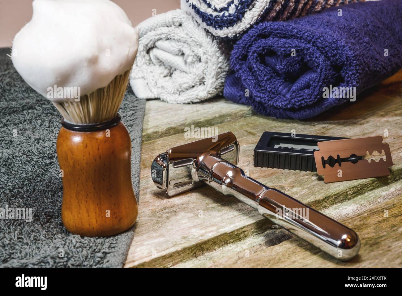 Horizontal close-up photo of wet shaving supplies. Shiny safety razor, lathered shaving brush ...