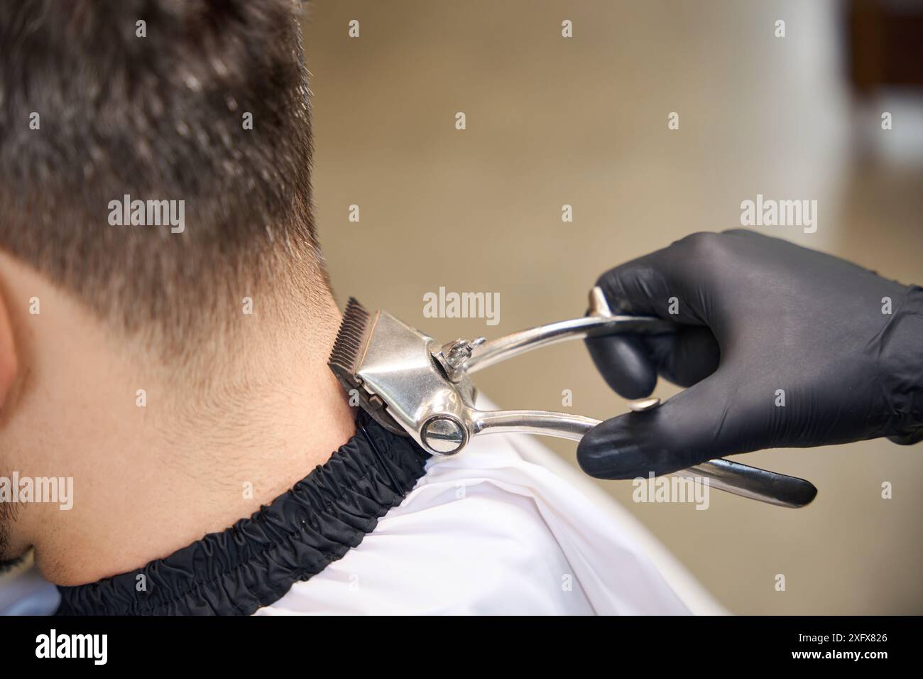 Close-up view barber using manual clipper to shave handsome man occiput ...
