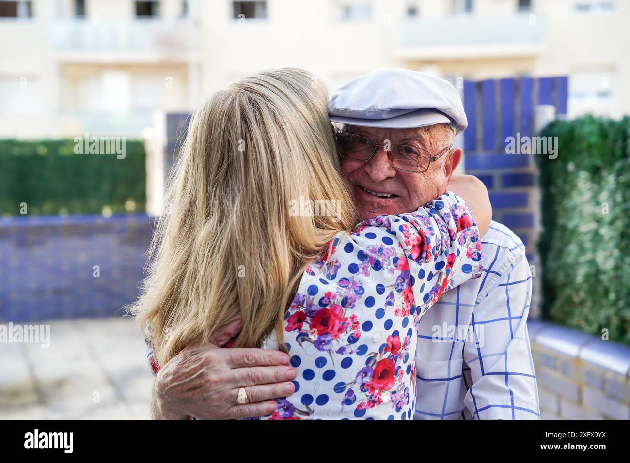 A woman hugs an older father in summertime. family having fun together ...