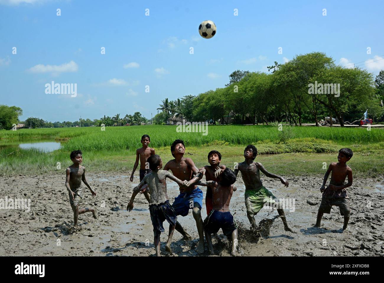 The rural village children are playing football game in the muddy field ...