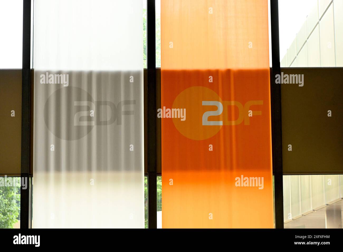 Logo auf Flaggen vor Fenster im Gegenlicht am ZDF-Gebaeude in Mainz ...