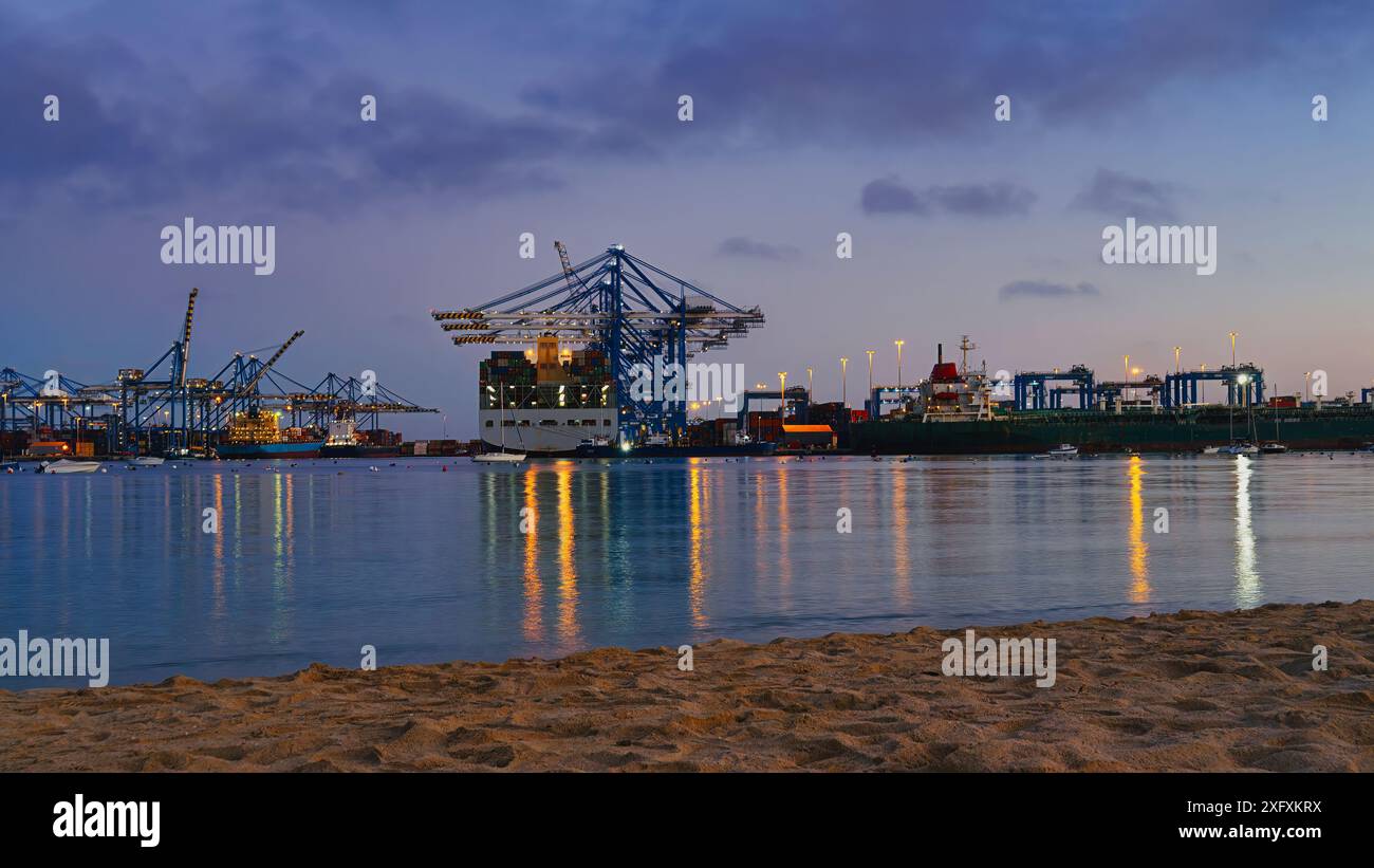 Bustling port scene at night featuring cargo ships, illuminated cranes ...