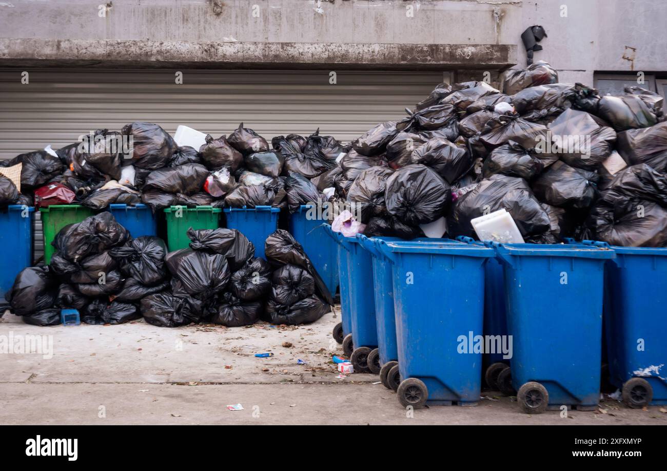 A pile of overflowing black garbage bags spilling over the top of ...