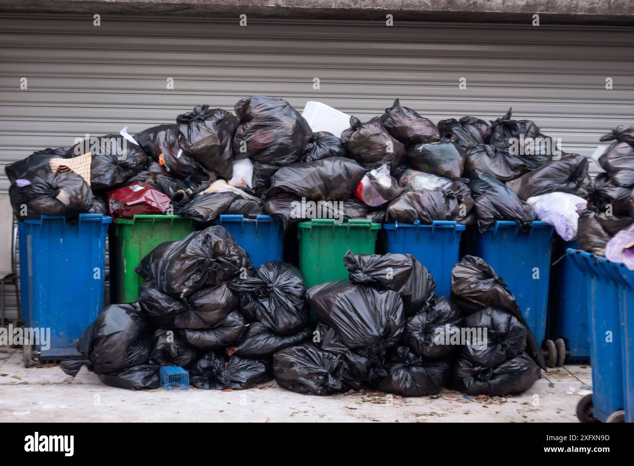 A pile of overflowing black garbage bags spilling over the top of ...