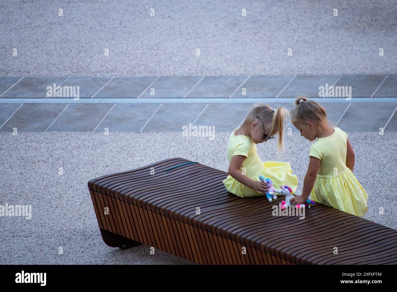 Twin sisters playing together on bench in park Stock Photo - Alamy