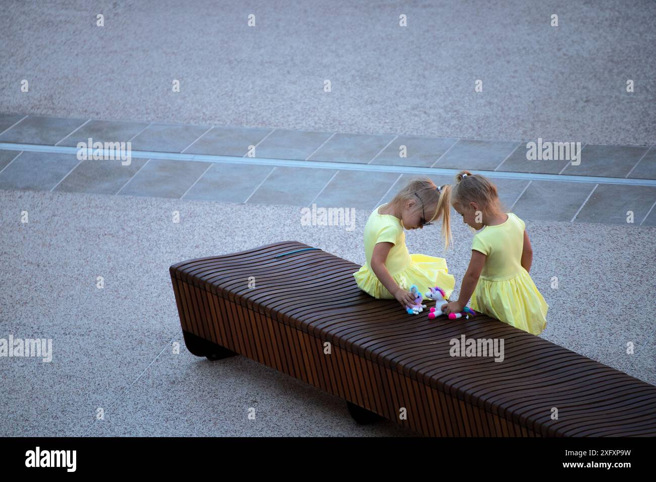 Twin sisters playing together on bench in park Stock Photo - Alamy