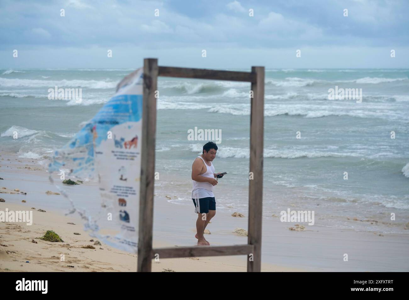A man walks on the beach in the aftermath of Hurricane Beryl in Tulum ...