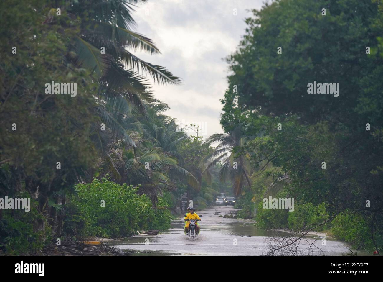A motorcyclist rides throw a street flooded by heavy rains from ...