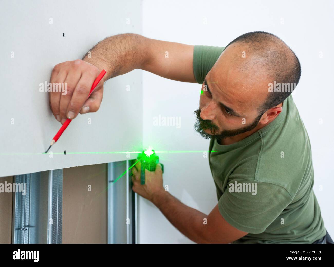 Worker building plasterboard wall. Working with cutting tools, fixing ...