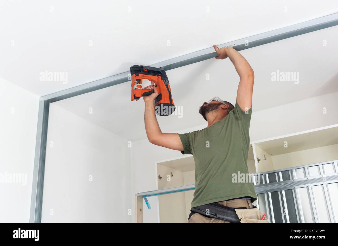 Worker building plasterboard wall. Working with cutting tools, fixing ...