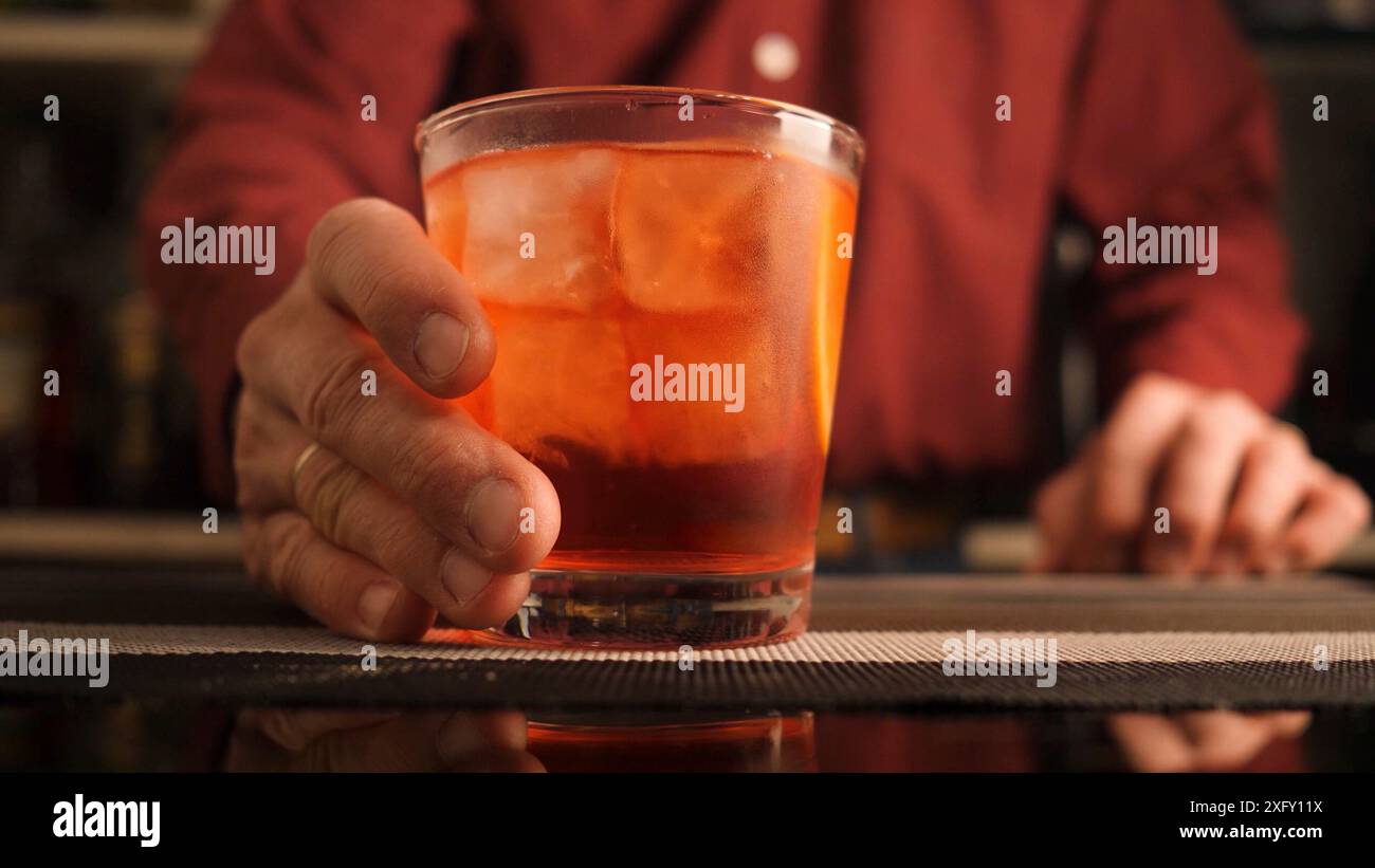 Bartender serves a Negroni cocktail on the bar counter Stock Photo - Alamy