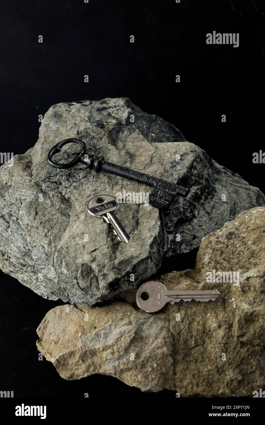 3 keys one old style 2 modern laying on rocks with black background ...