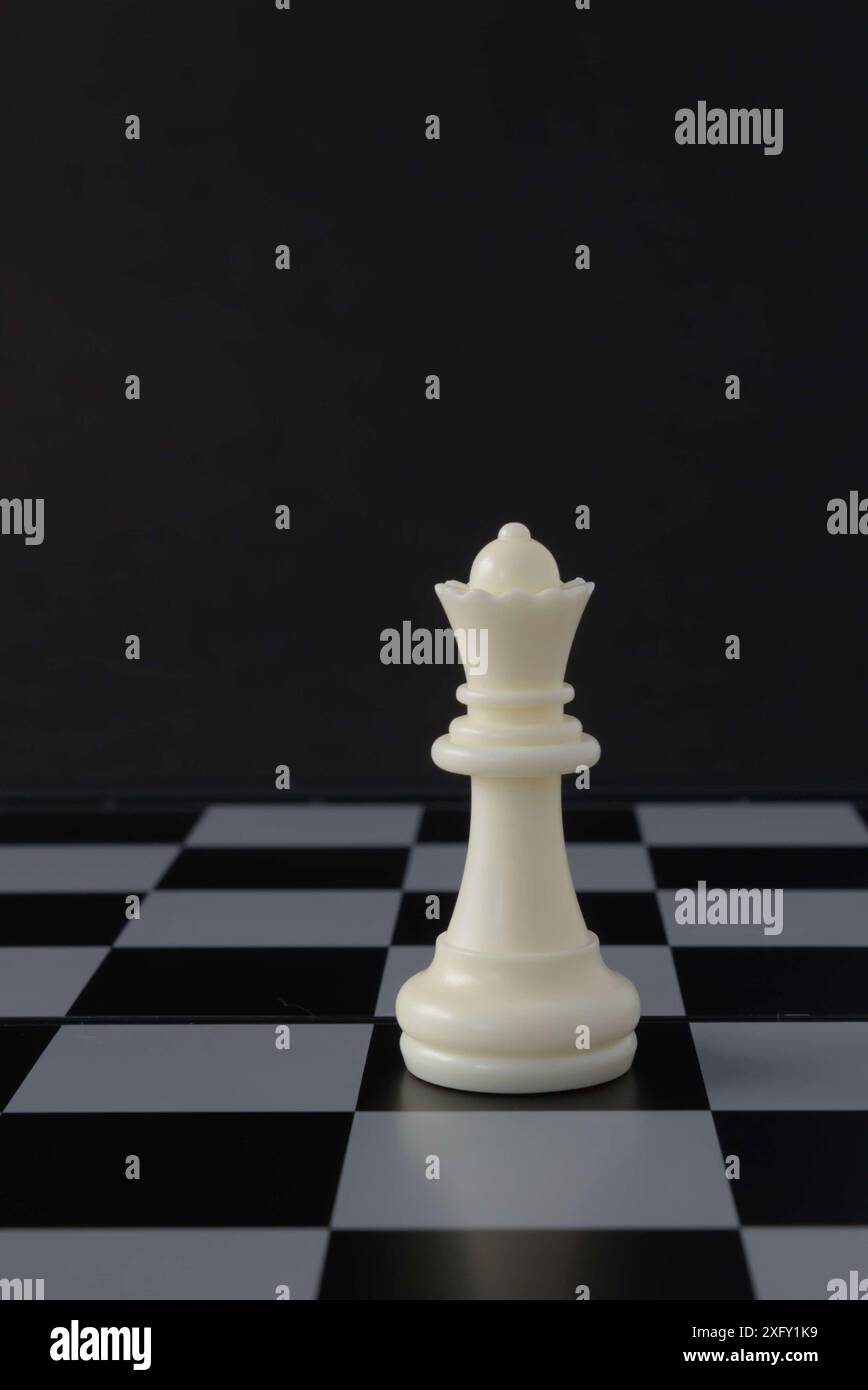 a single white queen chess piece alone on a chess board close up view ...