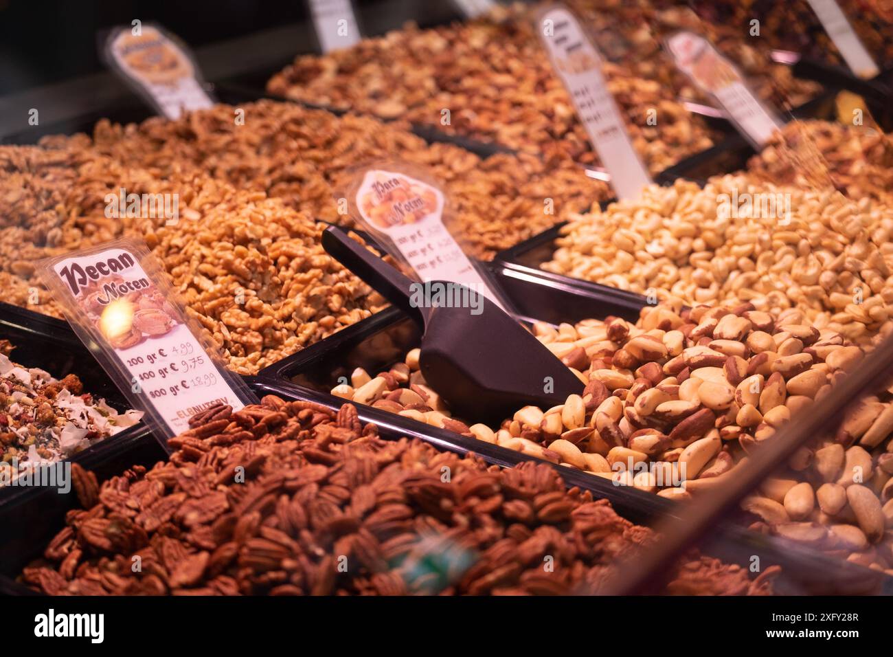 A variety of nuts are displayed in a store, including peanuts, cashews ...