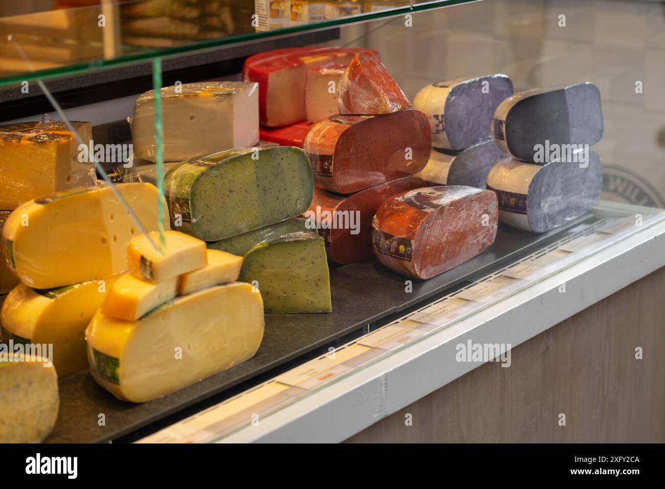 A display of cheese in a store. The cheese is in different colors and ...