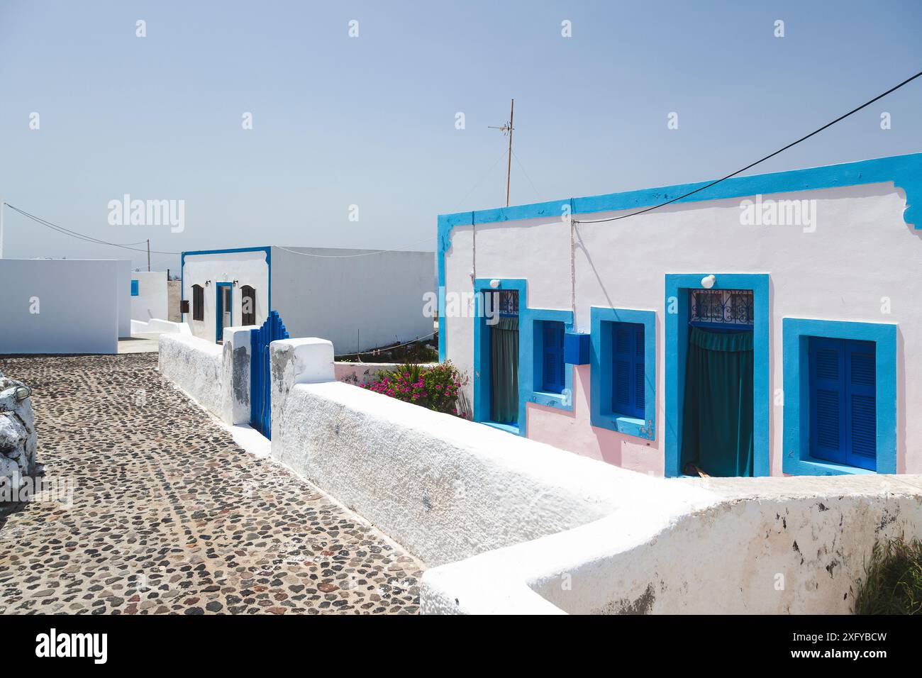 Traditional whitewashed houses with blue accents line a cobblestone ...