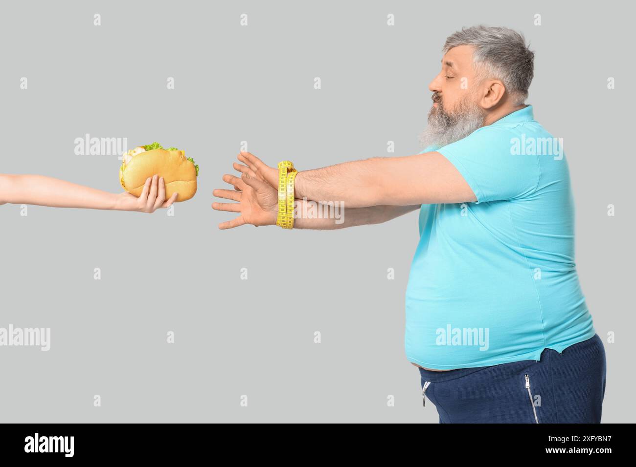 Overweight mature man hands tied with measuring tape on grey background ...